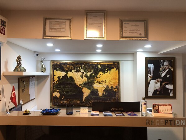 Bancada de recepção com certificados emoldurados, um grande mapa-múndi e um retrato.