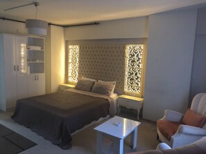 Quarto com cama grande, mesa de cabeceira, cadeira e guarda-roupa.