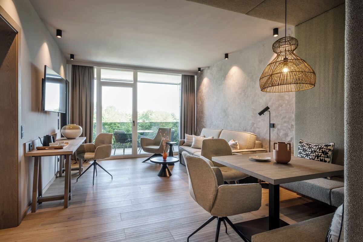 Uma sala de estar moderna com área de refeições, janelas amplas e luminária pendente.