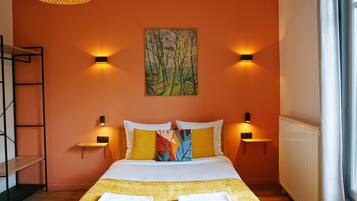 Quarto de hotel com uma cama, duas mesas de cabeceira, um quadro na parede e uma janela com cortinas.