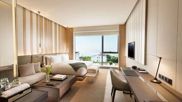 Quarto de hotel moderno com uma cama grande, um sofá, uma escrivaninha e uma televisão.