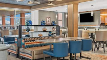 Uma área de bar moderna com assentos, televisão e copos decorativos.