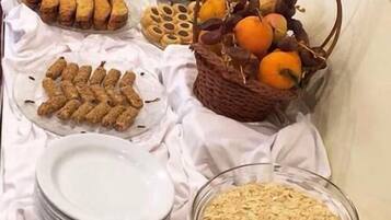 Mesa de buffet com diversos alimentos, incluindo bolachas, doces, frutas e cereais.