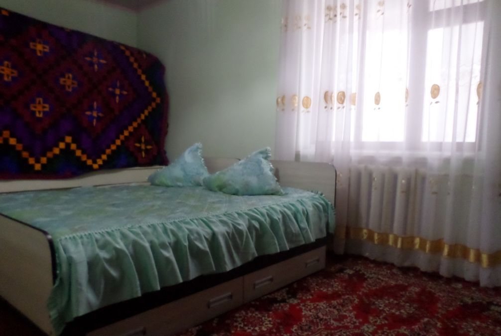 Um quarto com uma cama, uma janela com cortinas e um cobertor estampado na parede.