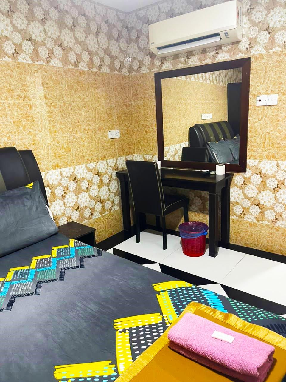 Quarto com cama, escrivaninha, cadeira, espelho e ar condicionado.