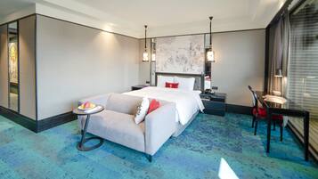 Quarto de hotel moderno com uma cama grande, mesas de cabeceira, uma escrivaninha e uma cadeira.