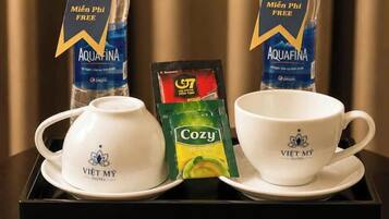 Uma bandeja com duas garrafas de água Aquafina, um sachê de chá Cozy e duas xícaras brancas com o logotipo do Hotel Viet My.