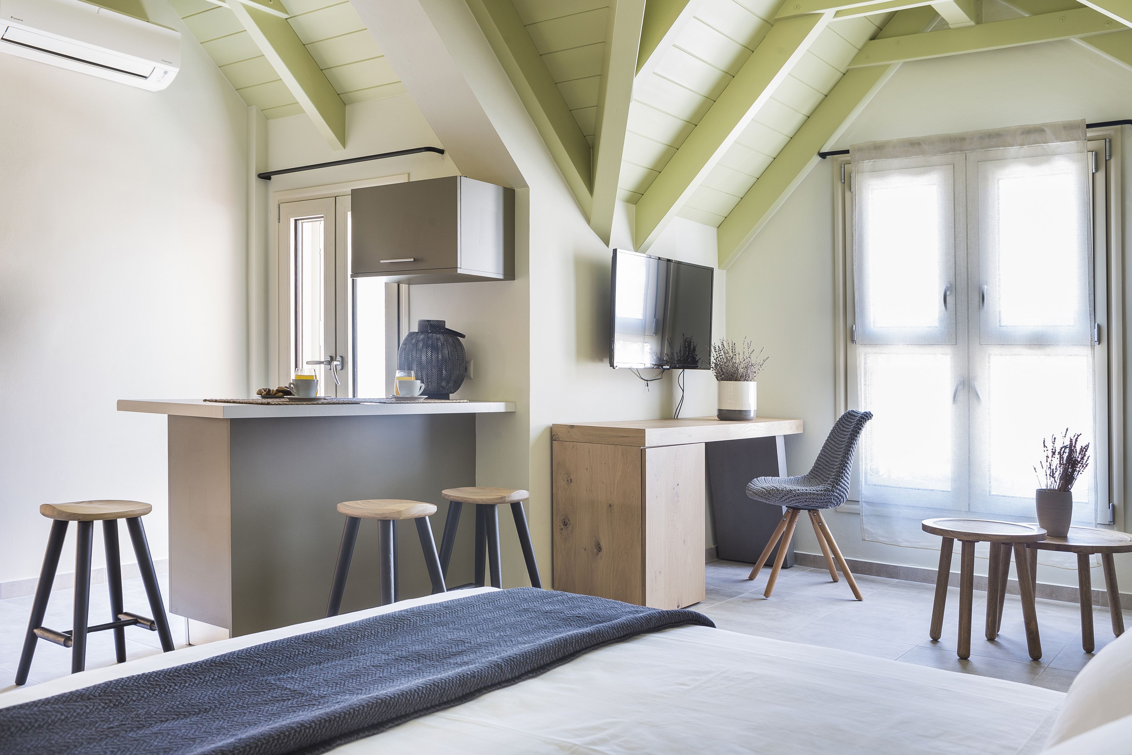 Quarto moderno com uma cama grande, uma kitchenette pequena, TV e janela com vista.