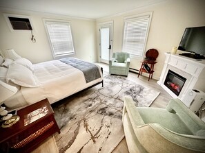 Um quarto com uma cama, uma cadeira, uma lareira e uma televisão.