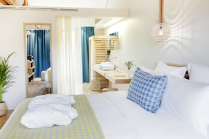 Quarto de hotel com cama, banheiro, espelho e luminária pendente.