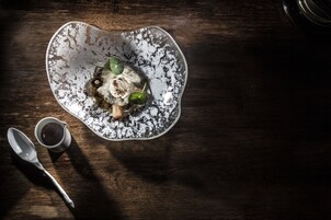 Prato em formato de coração com uma sobremesa sobre uma mesa de madeira.
