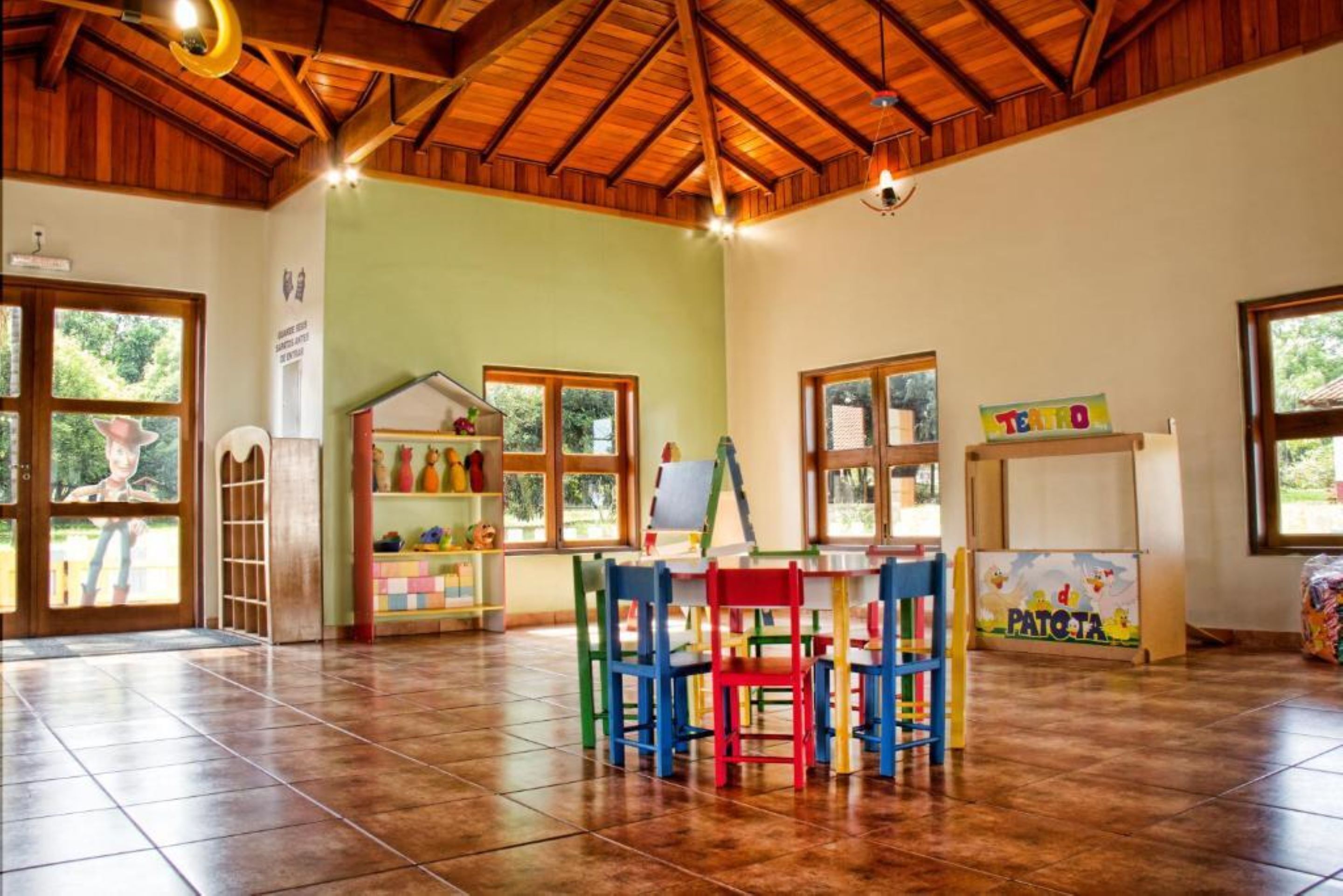 Um quarto amplo com teto de madeira alto, janelas grandes e piso de azulejos.