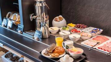 Buffet com diversos alimentos, incluindo pão, queijo, carnes e frutas.