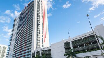 Um edifício alto com design moderno, com várias sacadas e uma faixa vermelha marcante.