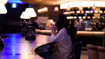 Uma mulher sentada em um bar com uma luminária à sua frente.