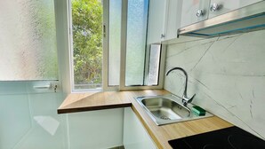 Cozinha moderna com pia de aço inoxidável, bancada de madeira e vista para o verde lá fora.