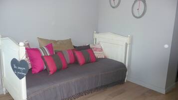Cama com cabeceira, várias almofadas, edredom escuro e uma decoração em formato de coração ao lado.