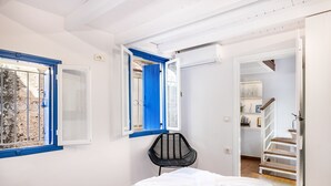 Quarto com cama, uma cadeira e escada que dá acesso a um patamar com prateleira.