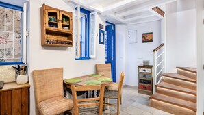 Uma sala de jantar com uma mesa e cadeiras de madeira, um armário com louças e uma escada.