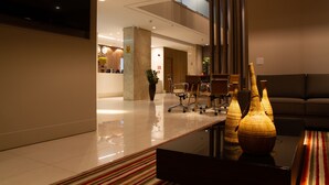 Um hall de hotel moderno com área de recepção, assentos e vasos decorativos.