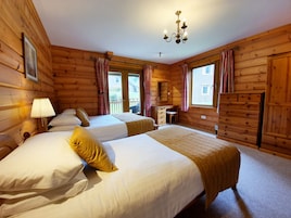 Quarto de cabana de madeira com duas camas, uma escrivaninha e um candelabro.