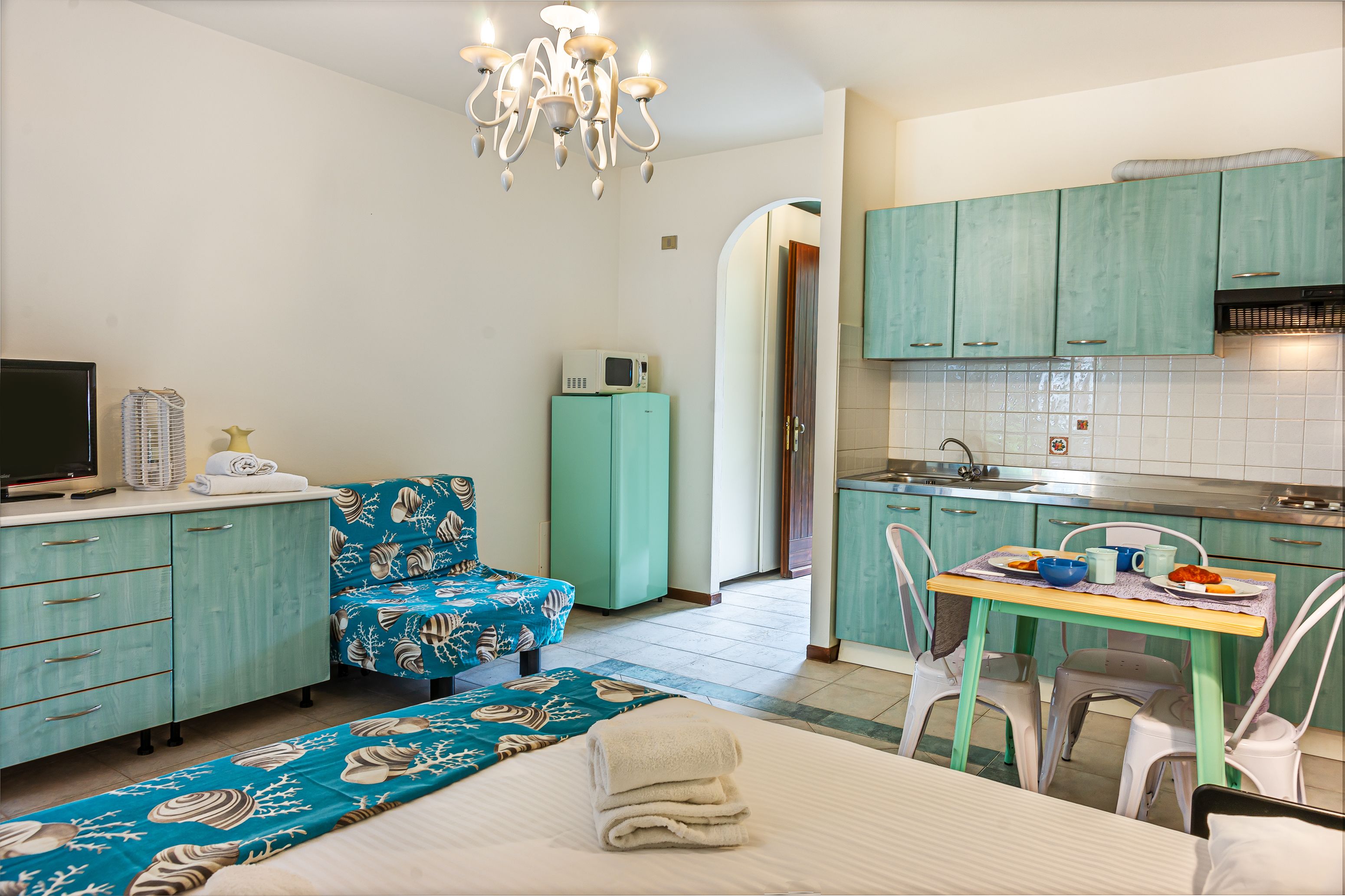 Quarto de hotel compacto com cama, cozinha compacta, área de refeições e banheiro.