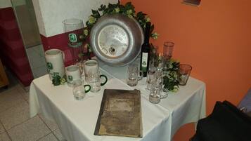 Uma mesa com diversos objetos de vidro, incluindo canecas de cerveja e copos, uma panela de metal e um livro intitulado