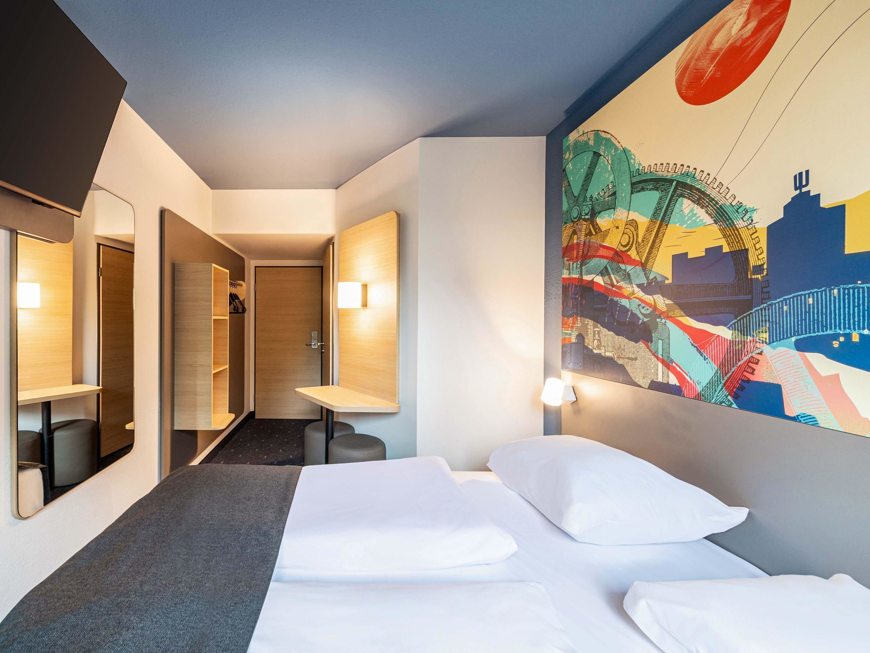 Quarto de hotel com cama, escrivaninha e banheiro.