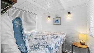 Quarto com cama, abajur, relógio de parede e quadro emoldurado.
