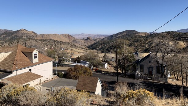 Área residencial com casas, céu claro e paisagem montanhosa ao fundo.