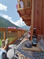 Um deck de madeira com uma mesa, uma garrafa de cerveja e um copo.