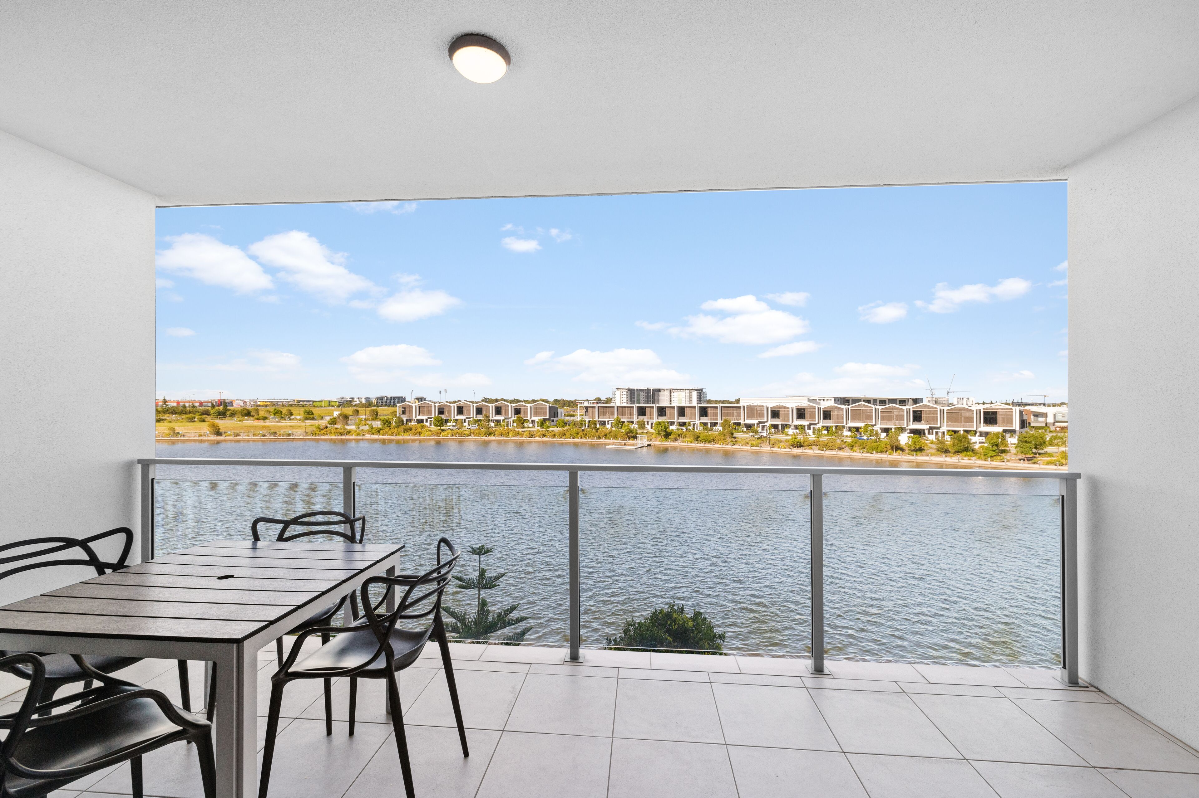Uma varanda com vista para um lago e edifícios ao longe.