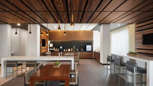 Cozinha moderna com ilha central, bancada para refeições e iluminação pendente.