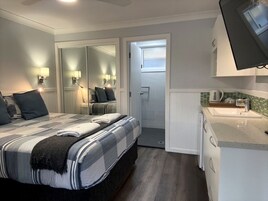 Quarto com cama, luminárias de cabeceira, closet espaçoso e banheiro com chuveiro.