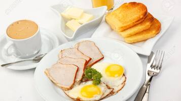 Prato de pequeno-almoço com fiambre, ovos, torradas e uma chávena de café.