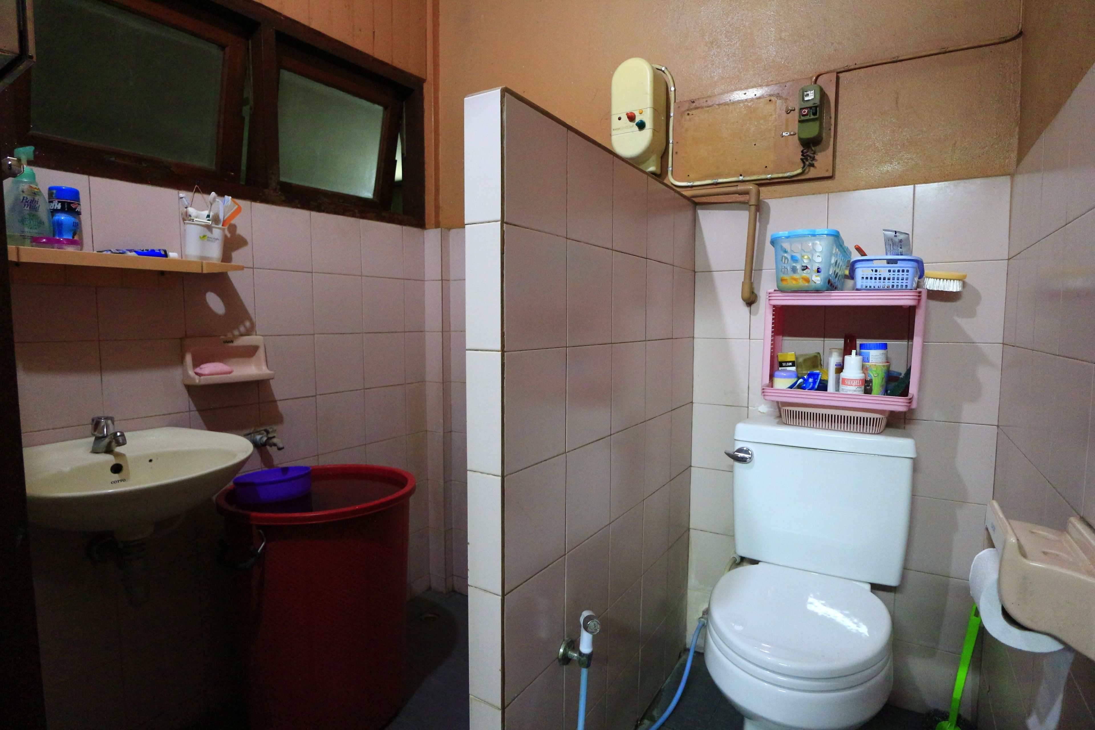 Casa de banho com lavatório, sanita e um barril vermelho.