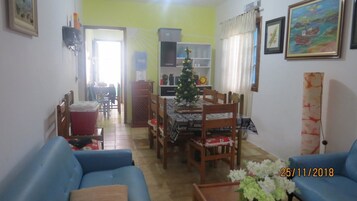 Sala de estar com mesa de jantar, sofá azul e árvore de Natal.