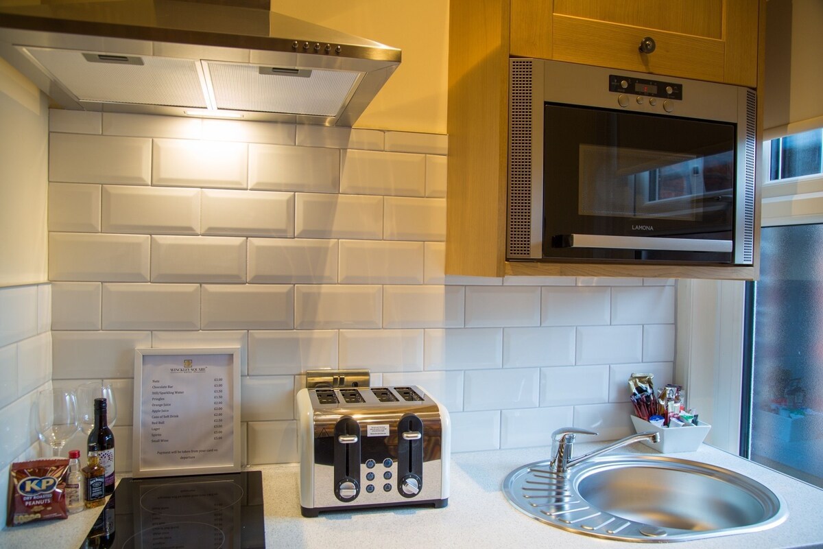 Uma cozinha equipada com forno embutido, torradeira, pia e um quadro de cardápio.