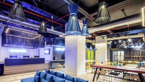 Um interior moderno com um sofá azul, luminárias pendentes e um balcão de recepção.