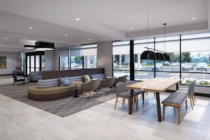 Um interior moderno com área de estar, mesa de jantar e grandes janelas com vista para o estacionamento.