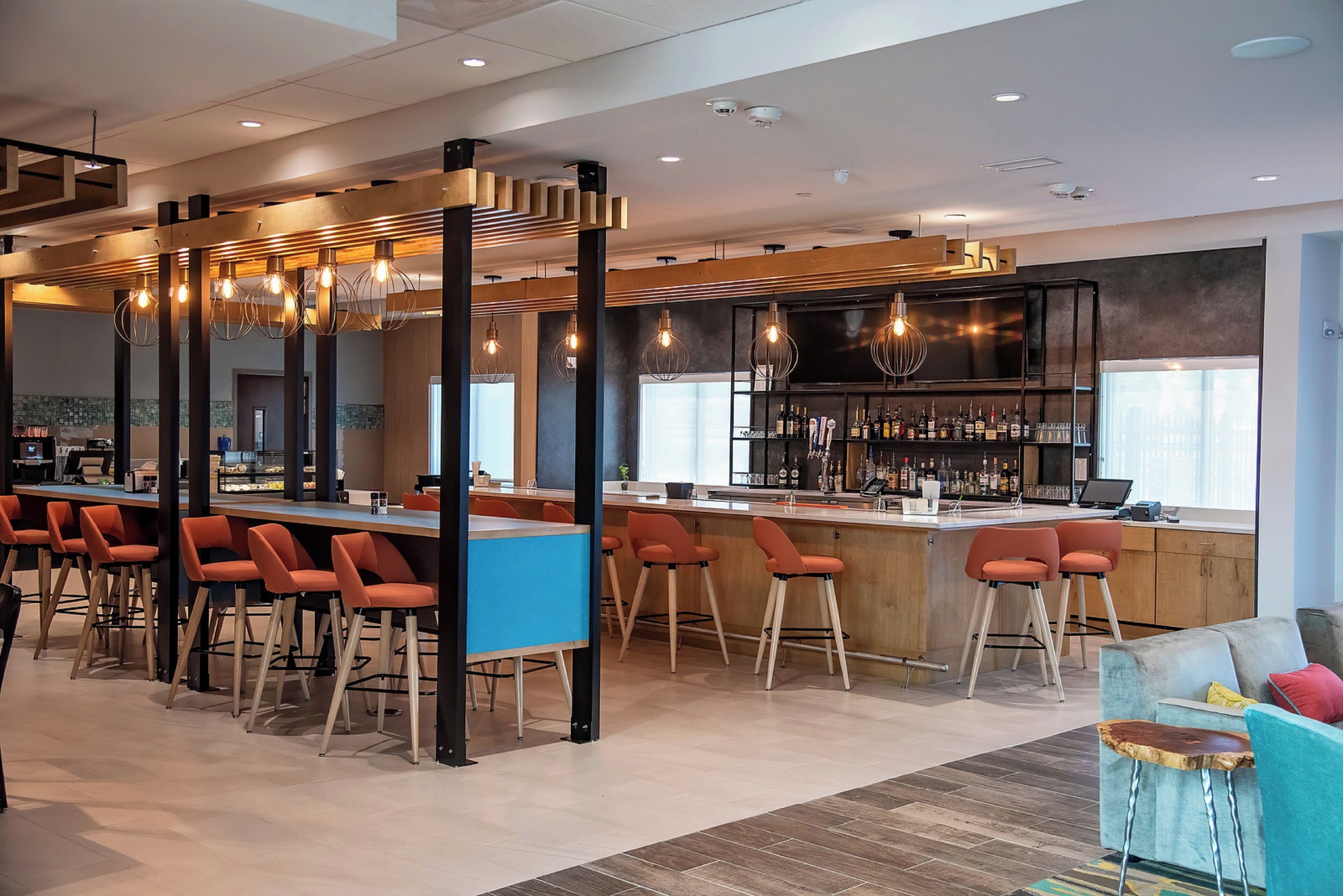 Uma área de bar moderna com diversas opções de assento, balcão e variedade de garrafas.