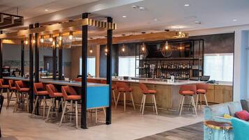 Uma área de bar moderna com diversas opções de assento, balcão e variedade de garrafas.