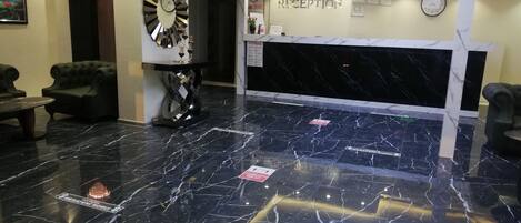 Uma área de recepção com piso de mármore, um relógio e um balcão de atendimento.