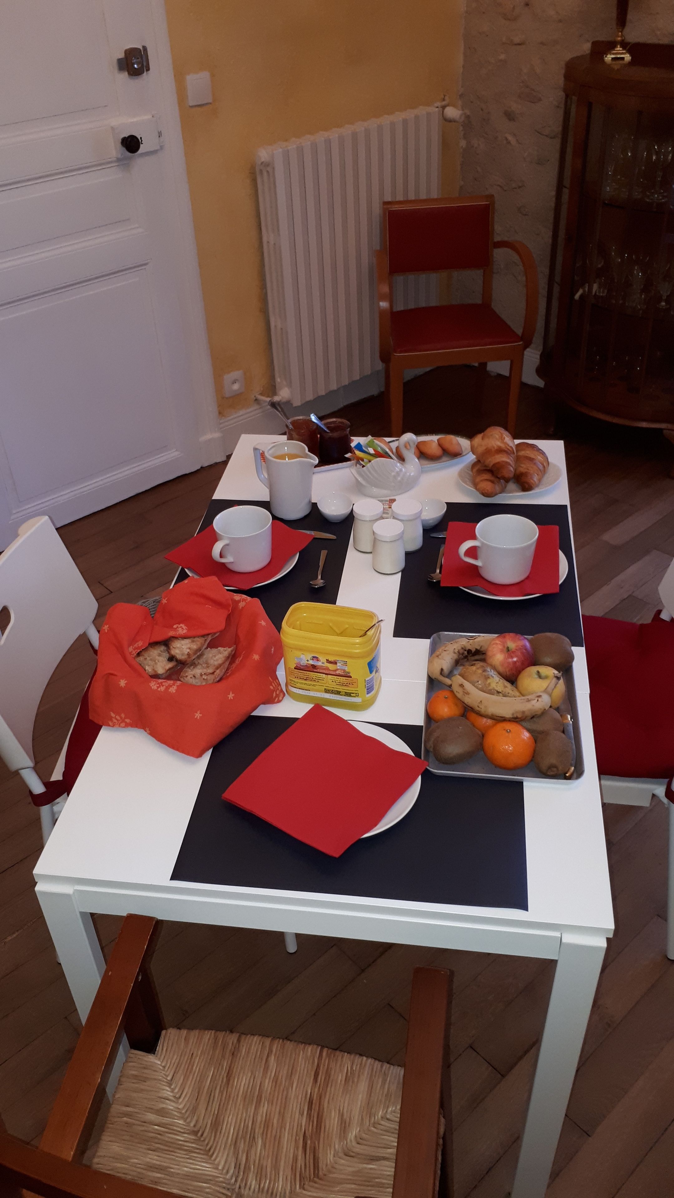 Mesa posta para o pequeno-almoço, com pão, pastelaria, frutas e acompanhamentos.
