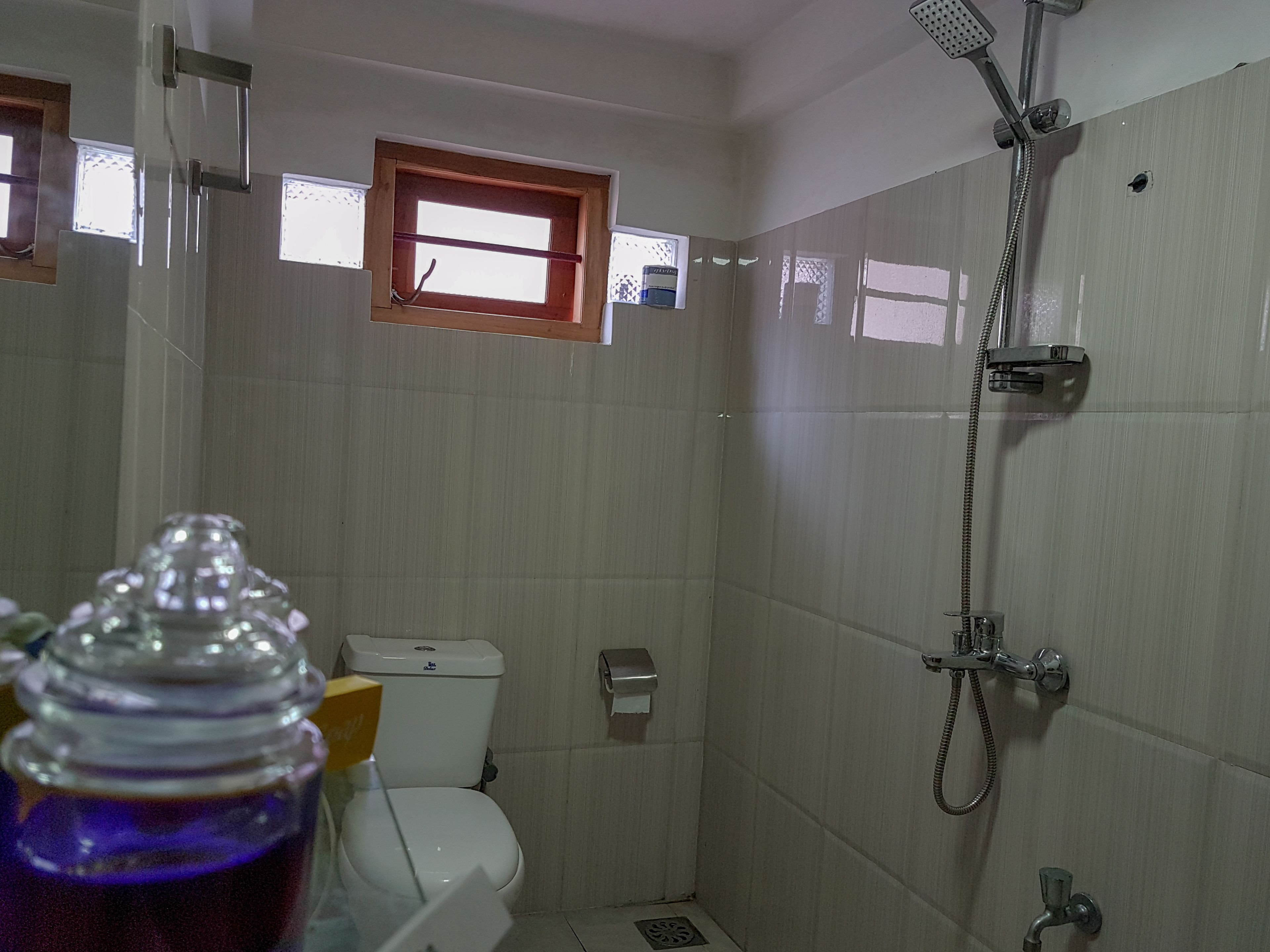 Um banheiro pequeno com vaso sanitário, chuveiro e janela.
