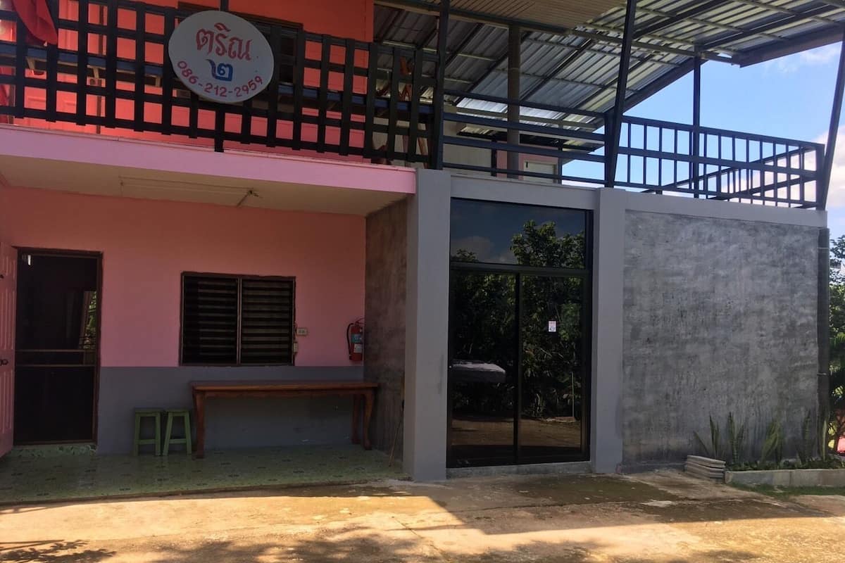 Um edifício com fachada rosa, uma varanda com grades de metal e uma grande porta de vidro.
