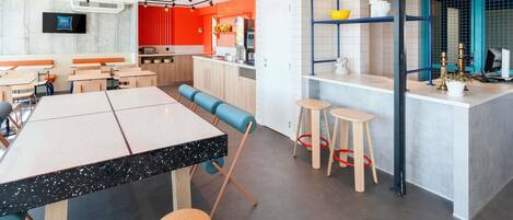 Uma cozinha moderna com uma ilha central, banquetas de bar e uma televisão na parede.