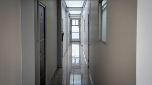 Um corredor com claraboia, portas e extintor de incêndio.