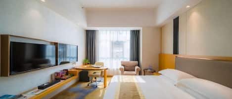 Quarto de hotel moderno com uma cama grande, televisão de tela plana na parede, escrivaninha com cadeira e janela com cortinas.