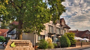 Um hotel com fachada de pedra, varanda e placa com a inscrição "Merfelder Hof Hotel & Restaurant".